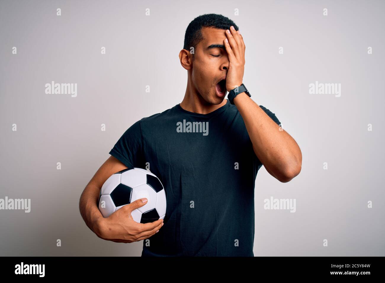 Handsome african american man playing footbal holding soccer ball over ...