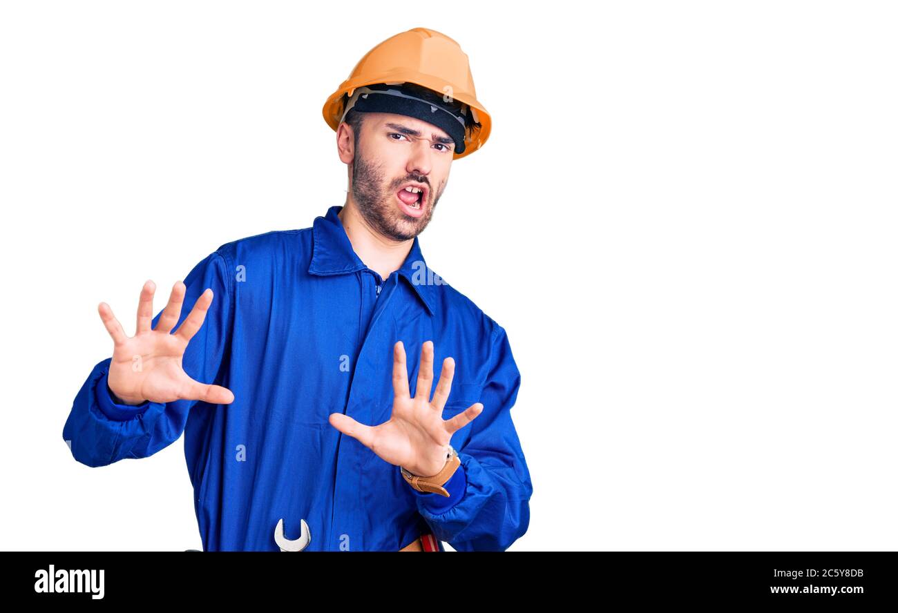Young hispanic man wearing worker uniform afraid and terrified with ...
