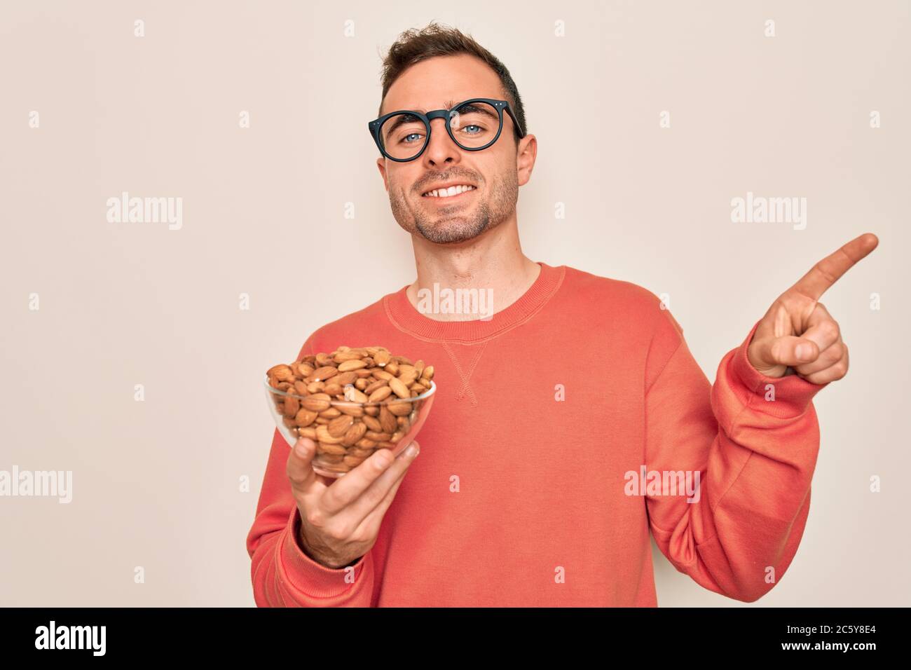 Handsome man with blue eyes holding bowl with healthy almonds snack ...