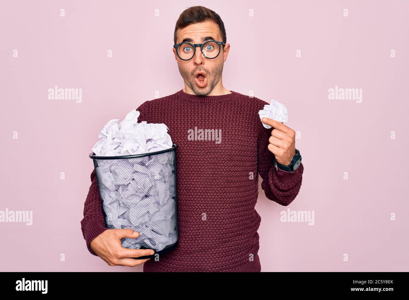 Handsome man with blue eyes wearing glasses holding full paper bin with ...
