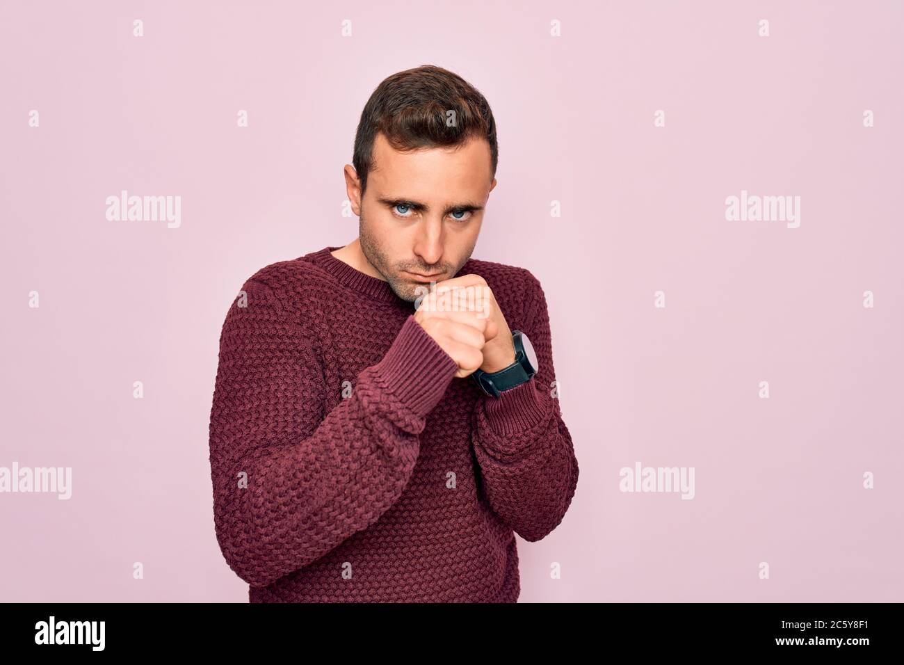 Young handsome man with blue eyes wearing casual sweater standing over ...