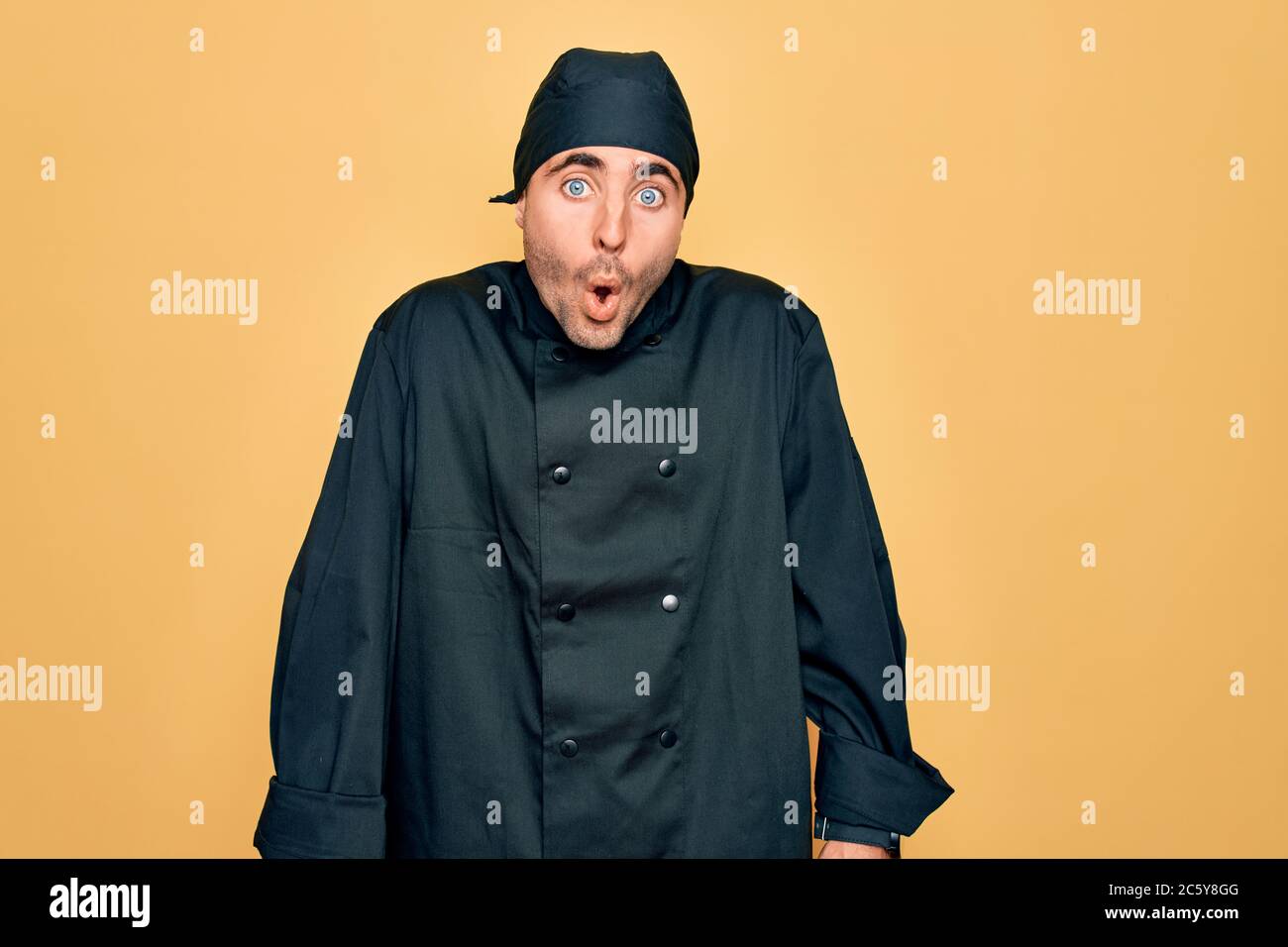 Young handsome cooker man with blue eyes wearing uniform and hat over ...