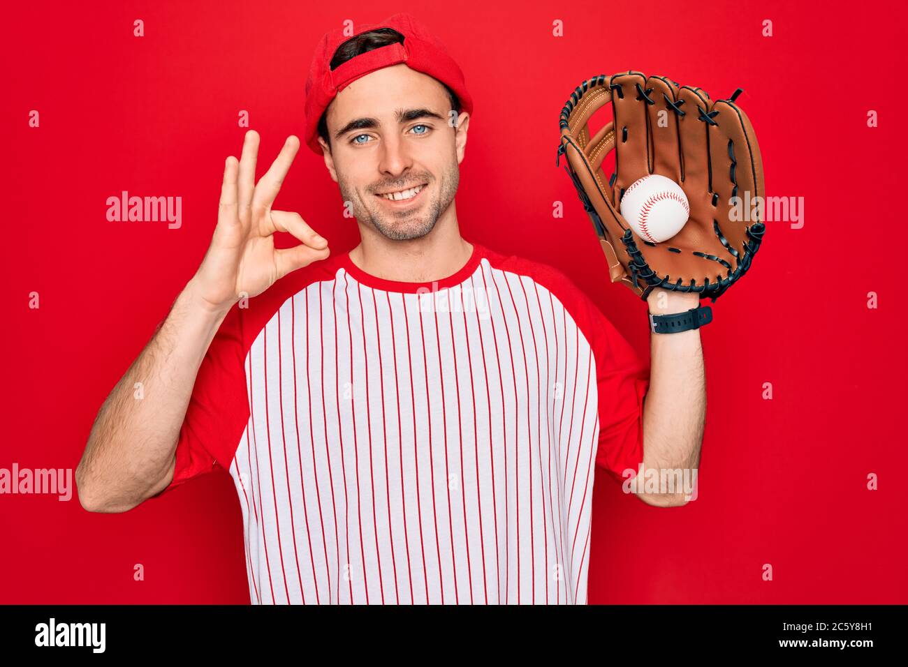 Young handsome sporty man with blue eyes playing baseball using glove ...