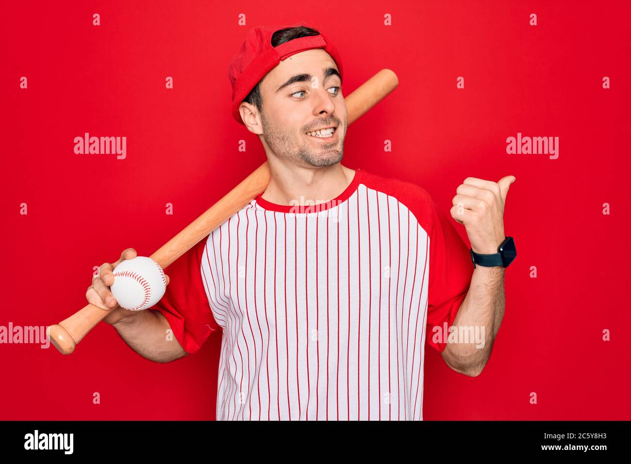 Young handsome sporty man with blue eyes playing baseball wearing cap ...