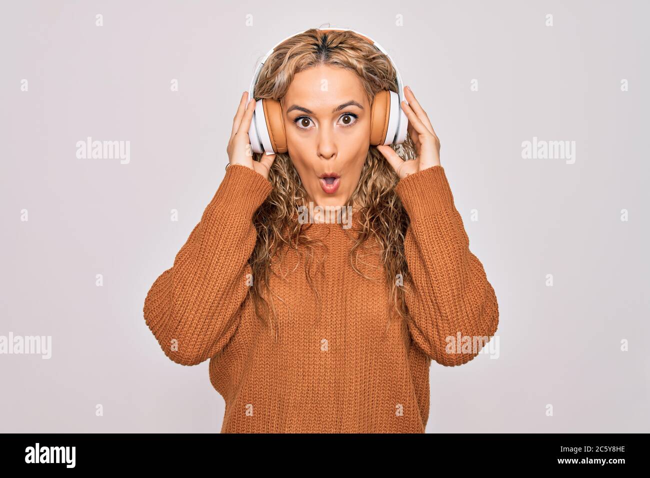 Young beautiful blonde woman listening to music using headphones over ...