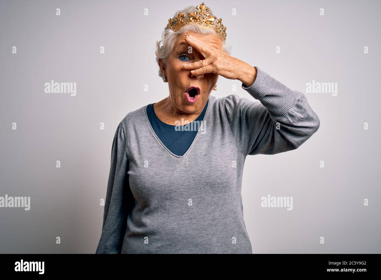 Senior beautiful grey-haired woman wearing golden queen crown over ...