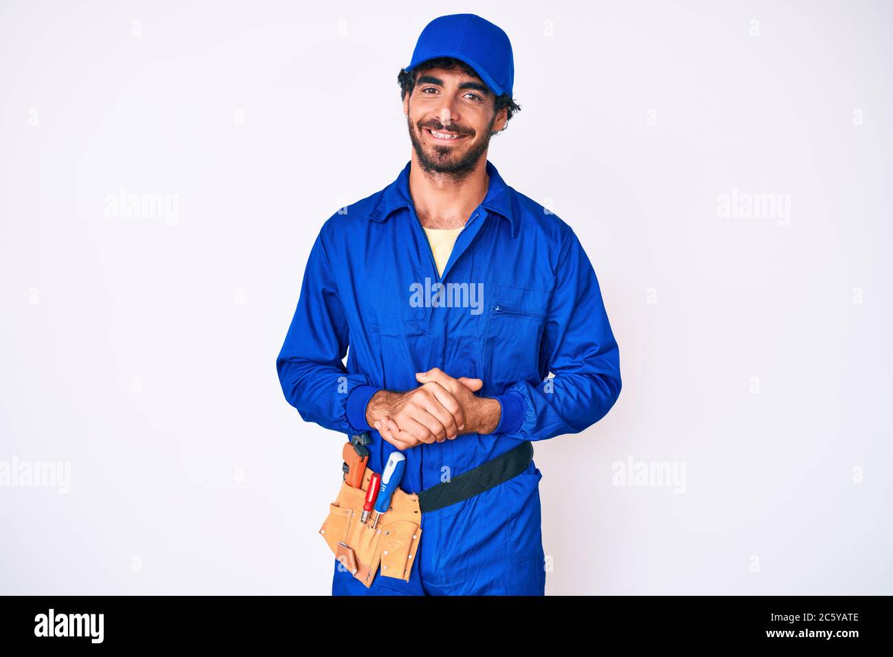 Handsome young man with curly hair and bear weaing handyman uniform ...