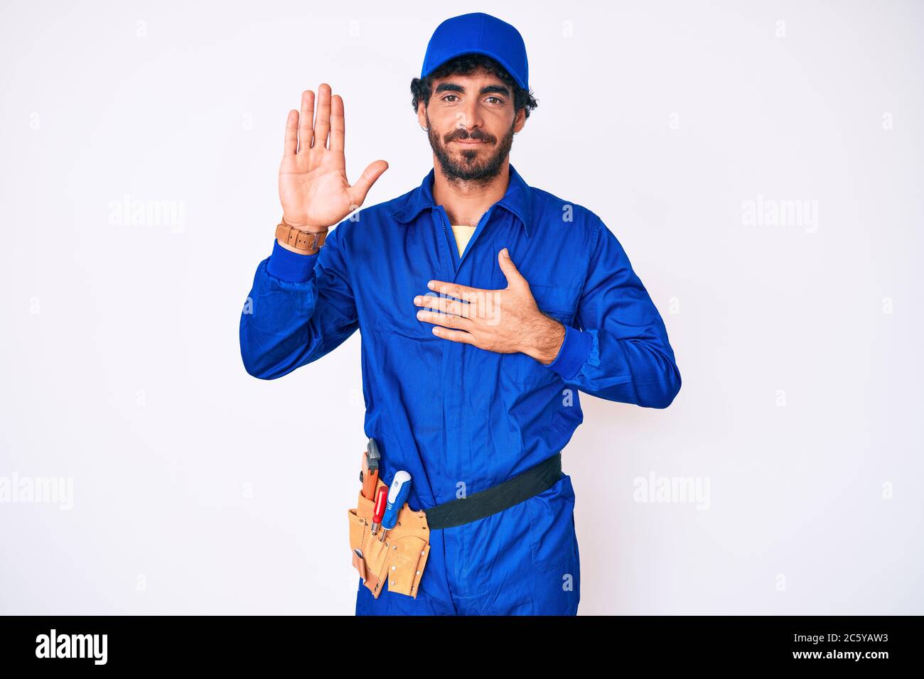 Handsome young man with curly hair and bear weaing handyman uniform ...