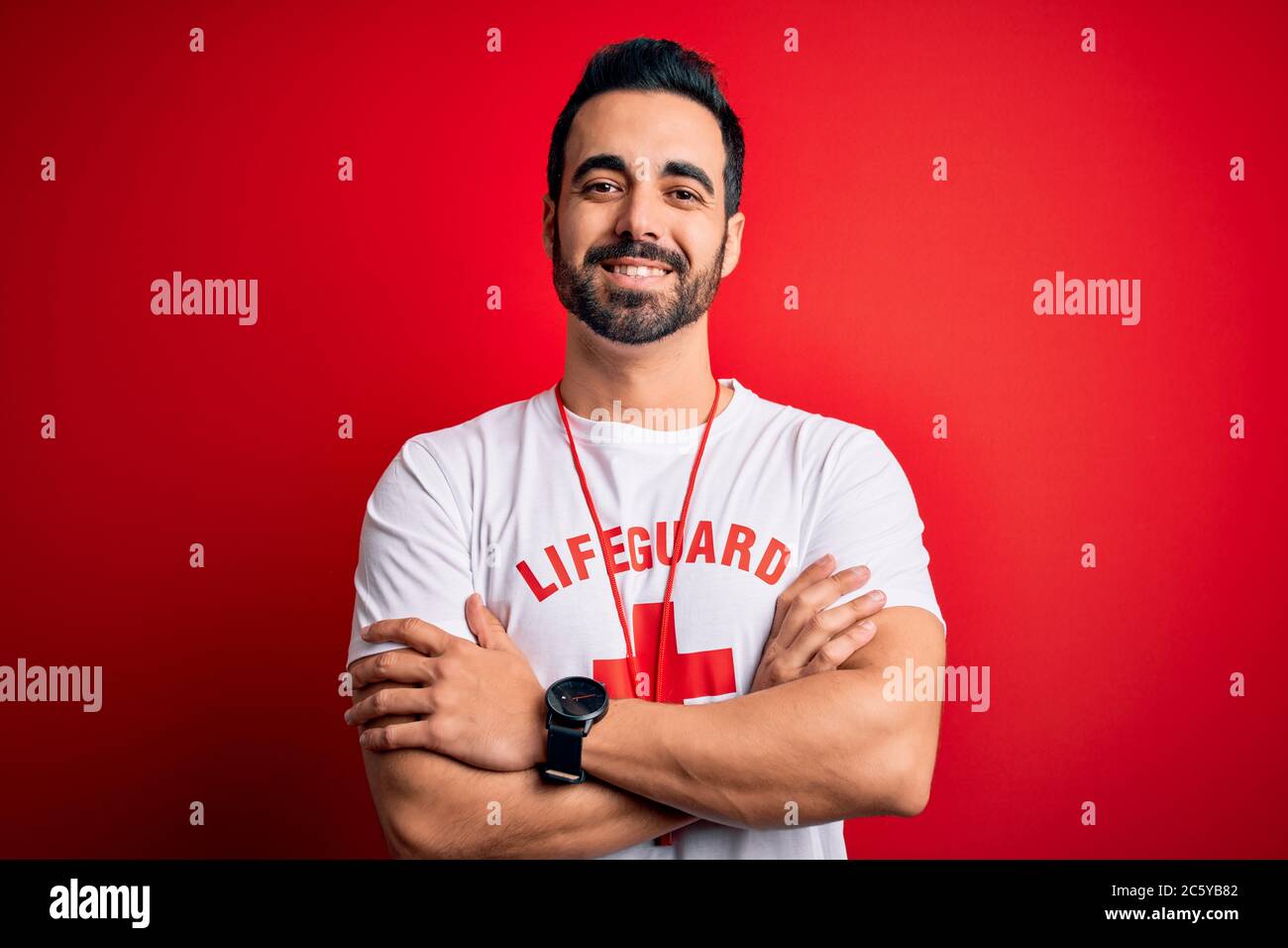 Young handsome lifeguard man with beard wearing whistle over isolated ...