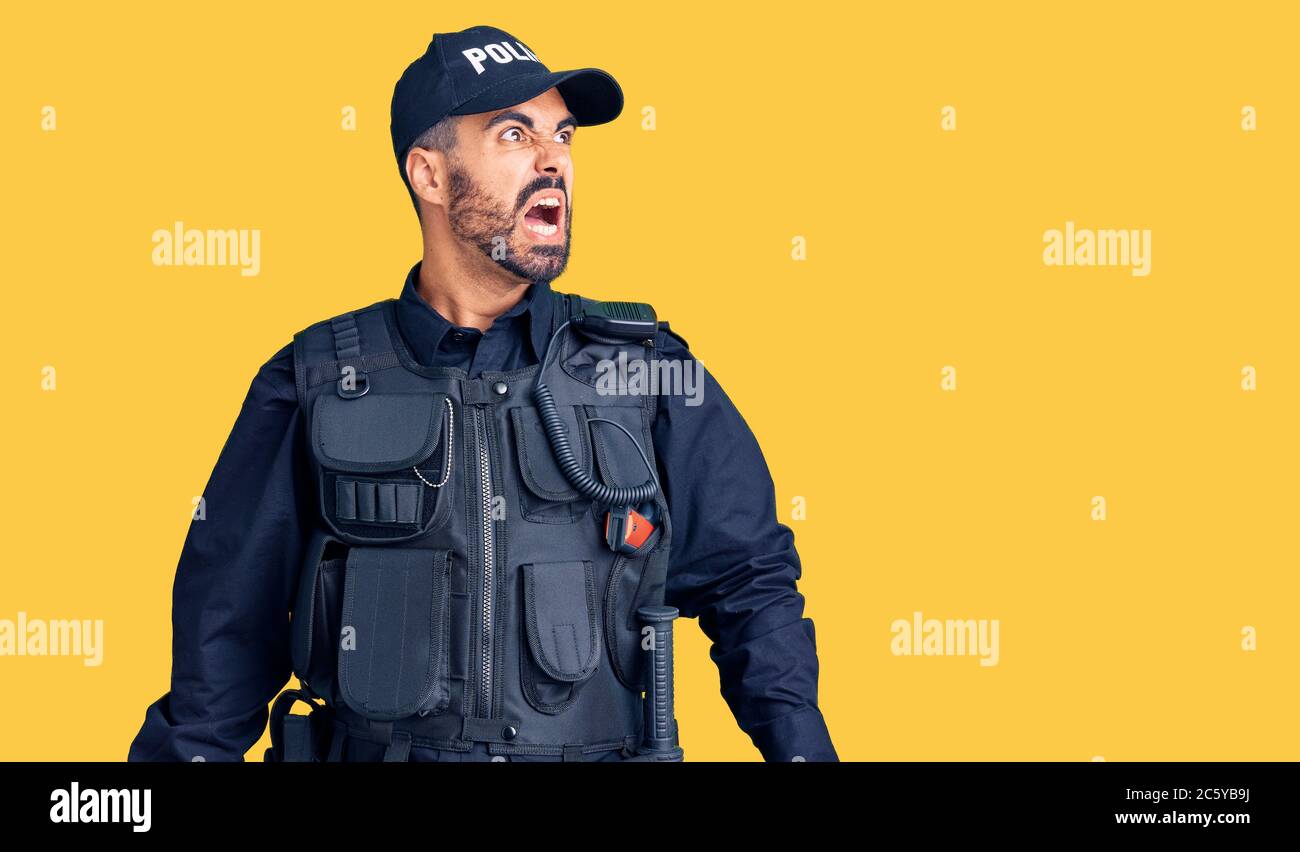 Young hispanic man wearing police uniform angry and mad screaming ...