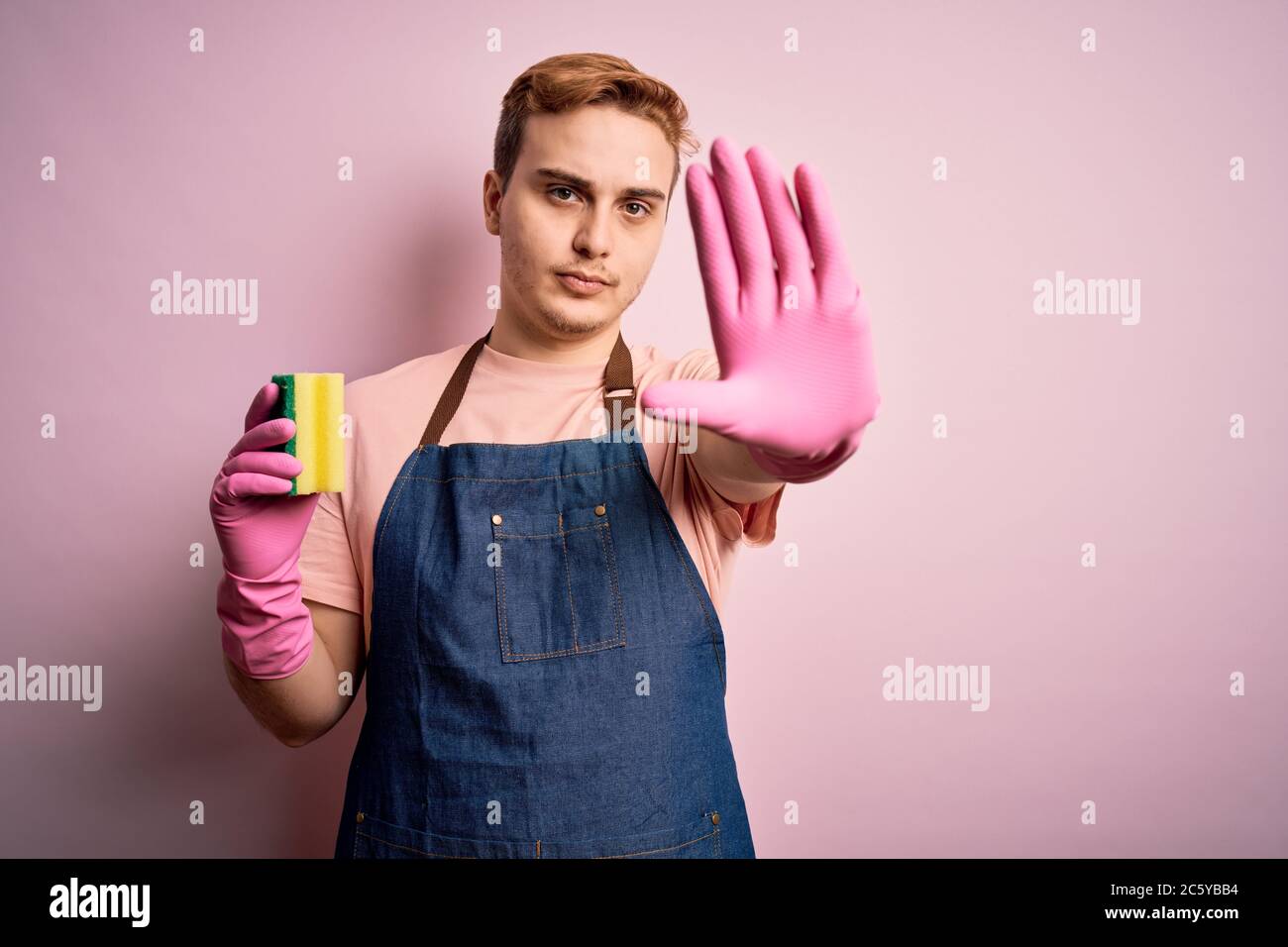 Handsome Redhead Man Doing Housework Wearing Apron And Gloves Using Cleaner Scourer With Open