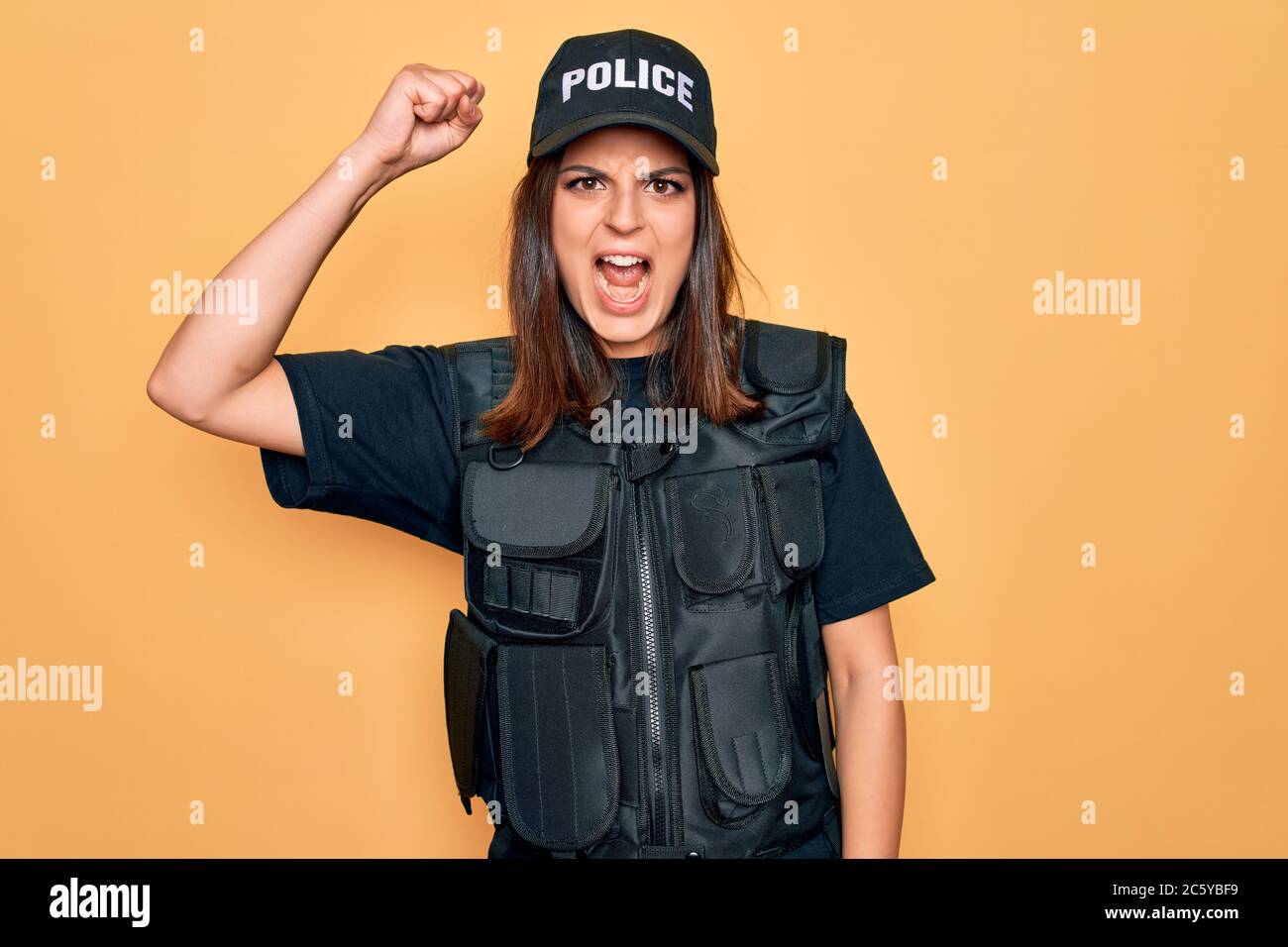 Young beautiful brunette policewoman wearing police uniform bulletproof ...