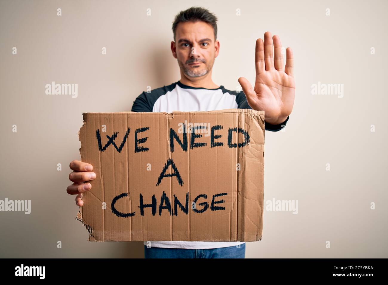 Young handsome activist man holding banner with change message over ...
