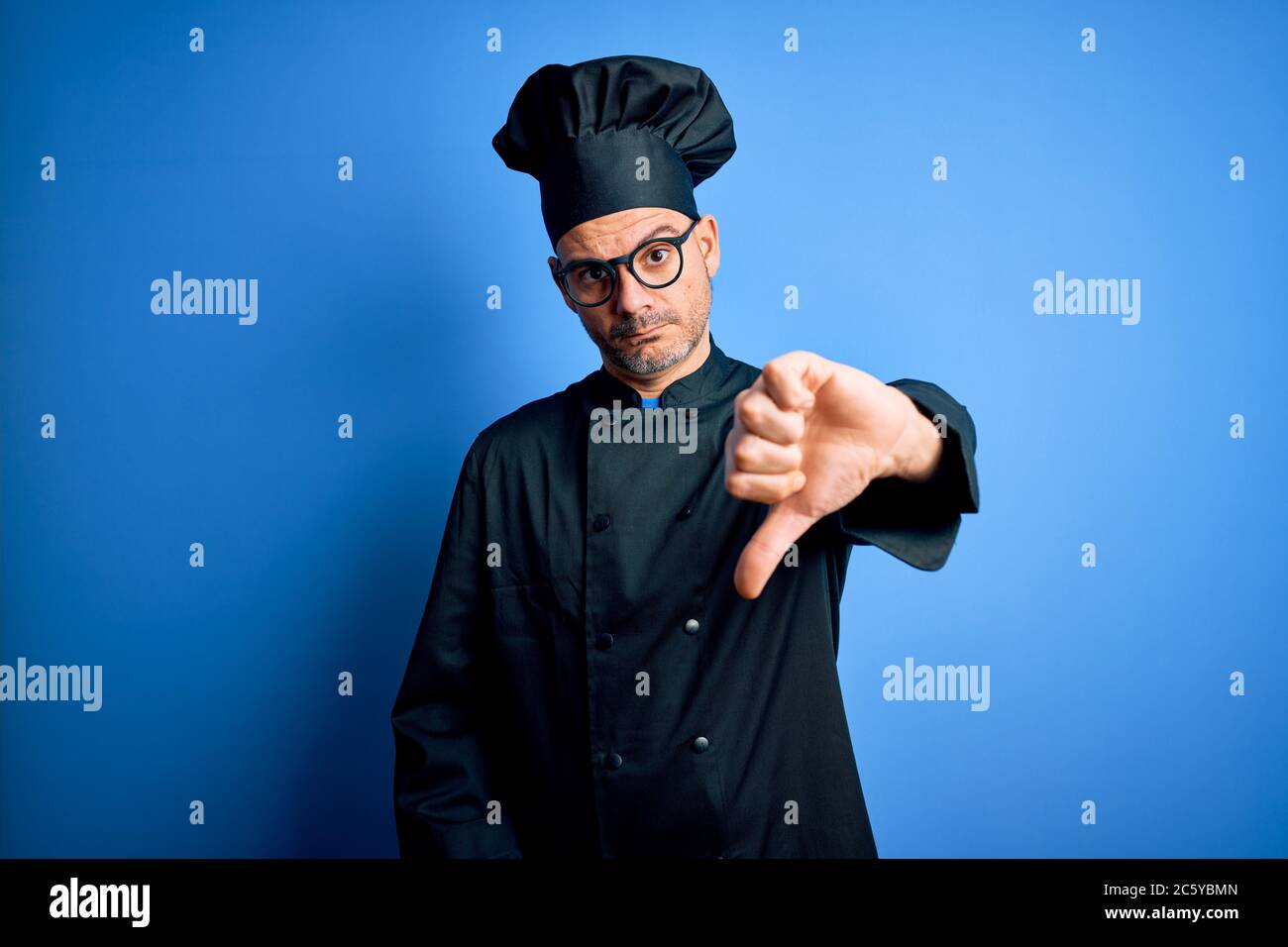Young handsome chef man wearing cooker uniform and hat over isolated ...