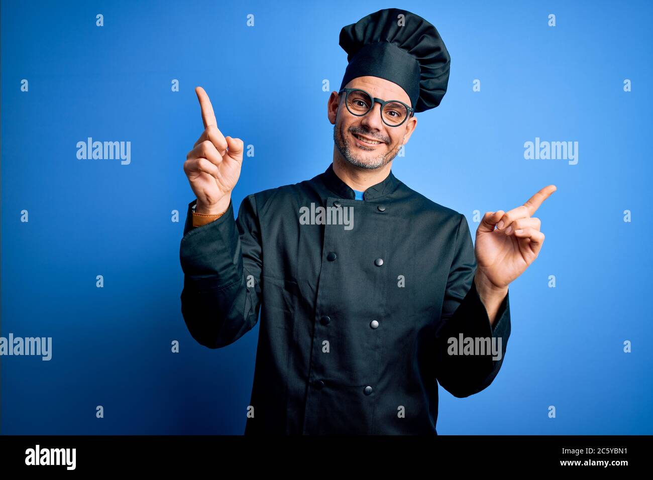Young handsome chef man wearing cooker uniform and hat over isolated ...