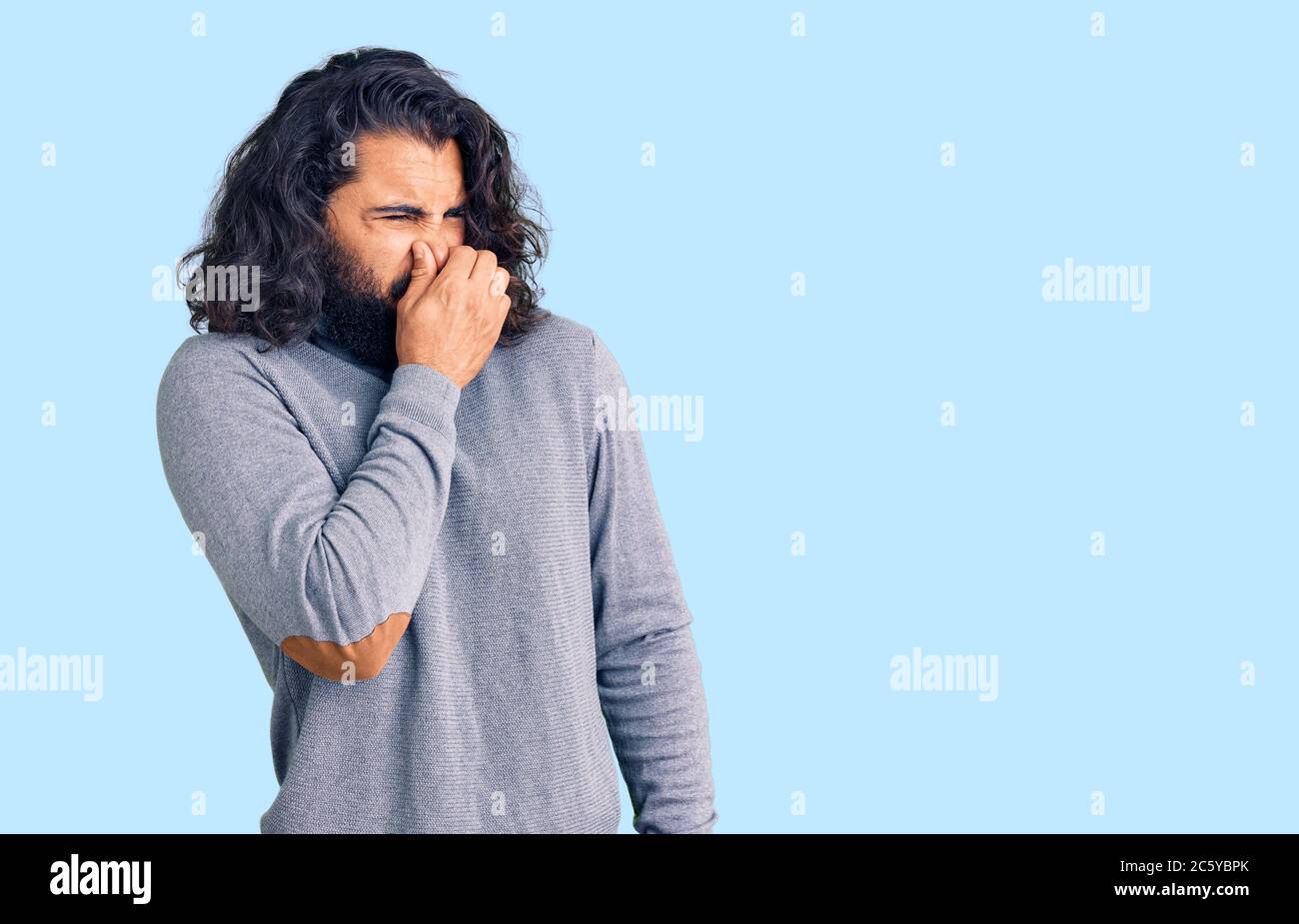 Young arab man wearing casual clothes smelling something stinky and ...