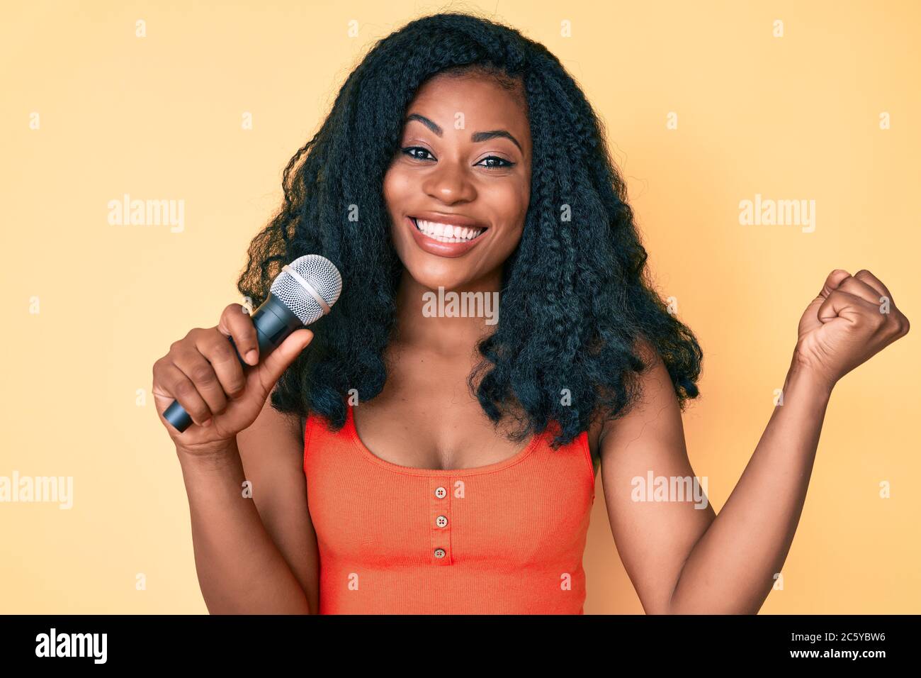 Beautiful african woman singing song using microphone screaming proud ...