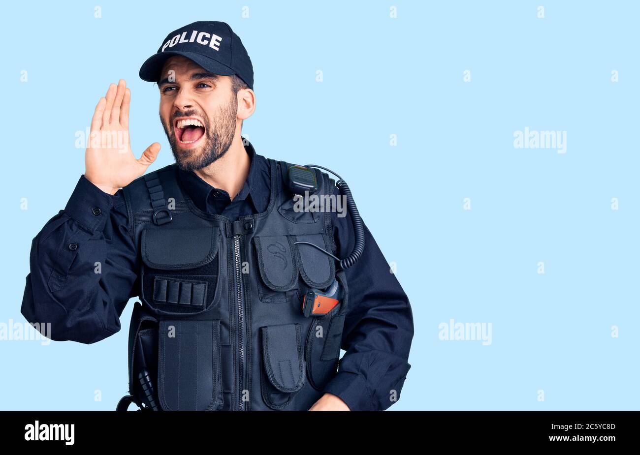Young handsome man with beard wearing police uniform shouting and ...