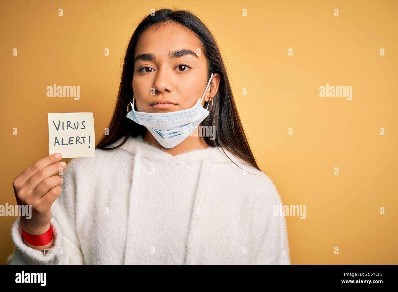 Young beautiful asian woman wearing medical mask holding paper with ...