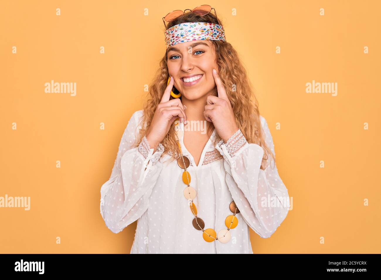 Young beautiful blonde hippie woman with blue eyes wearing sunglasses ...