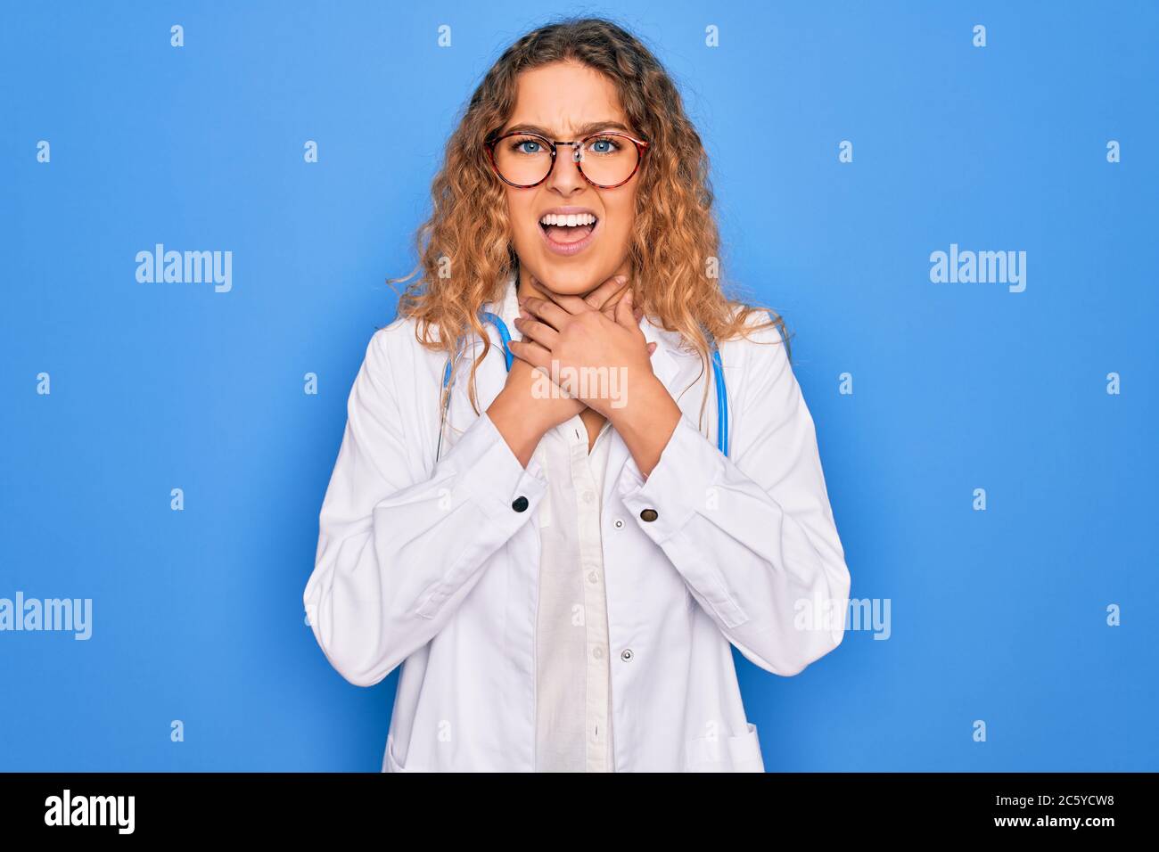 Young beautiful blonde doctor woman with blue eyes wearing coat and ...