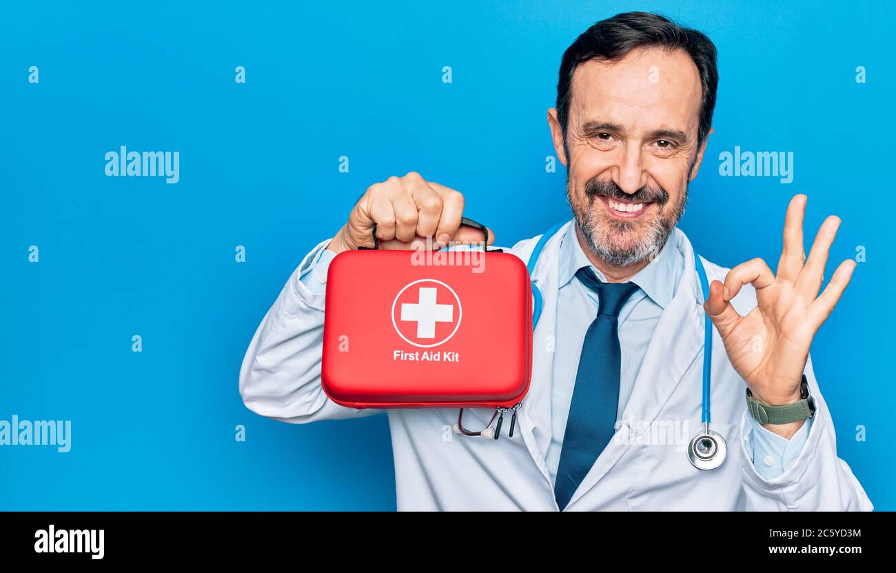 Middle age handsome doctor man wearing coat and stethoscope holding ...