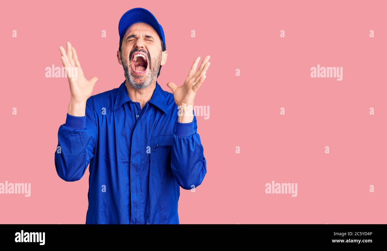 Middle age handsome man wearing mechanic uniform celebrating mad and ...