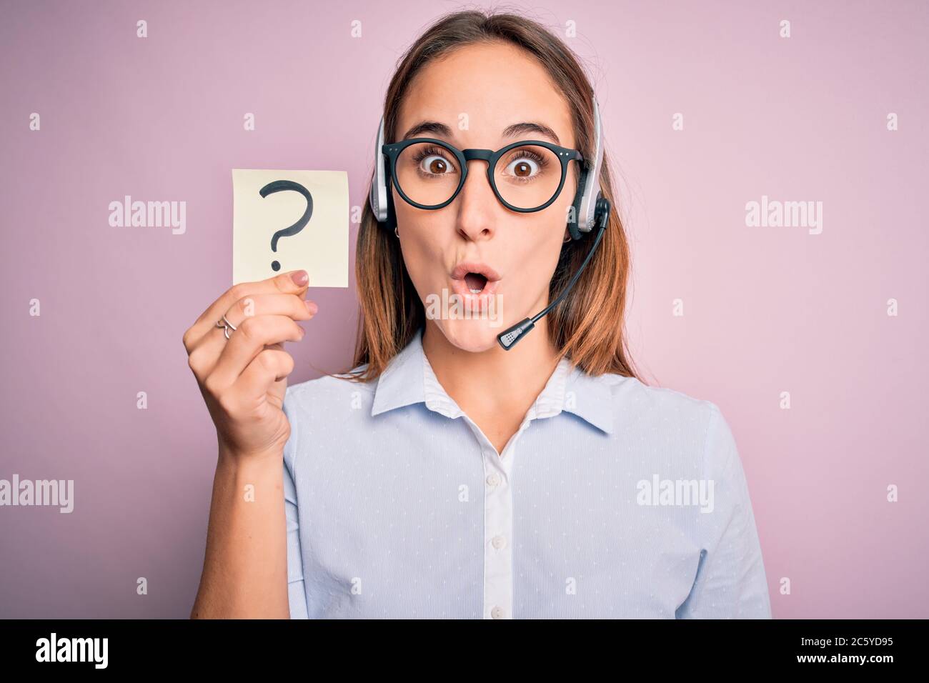 Beautiful call center agent woman working using headset holding ...