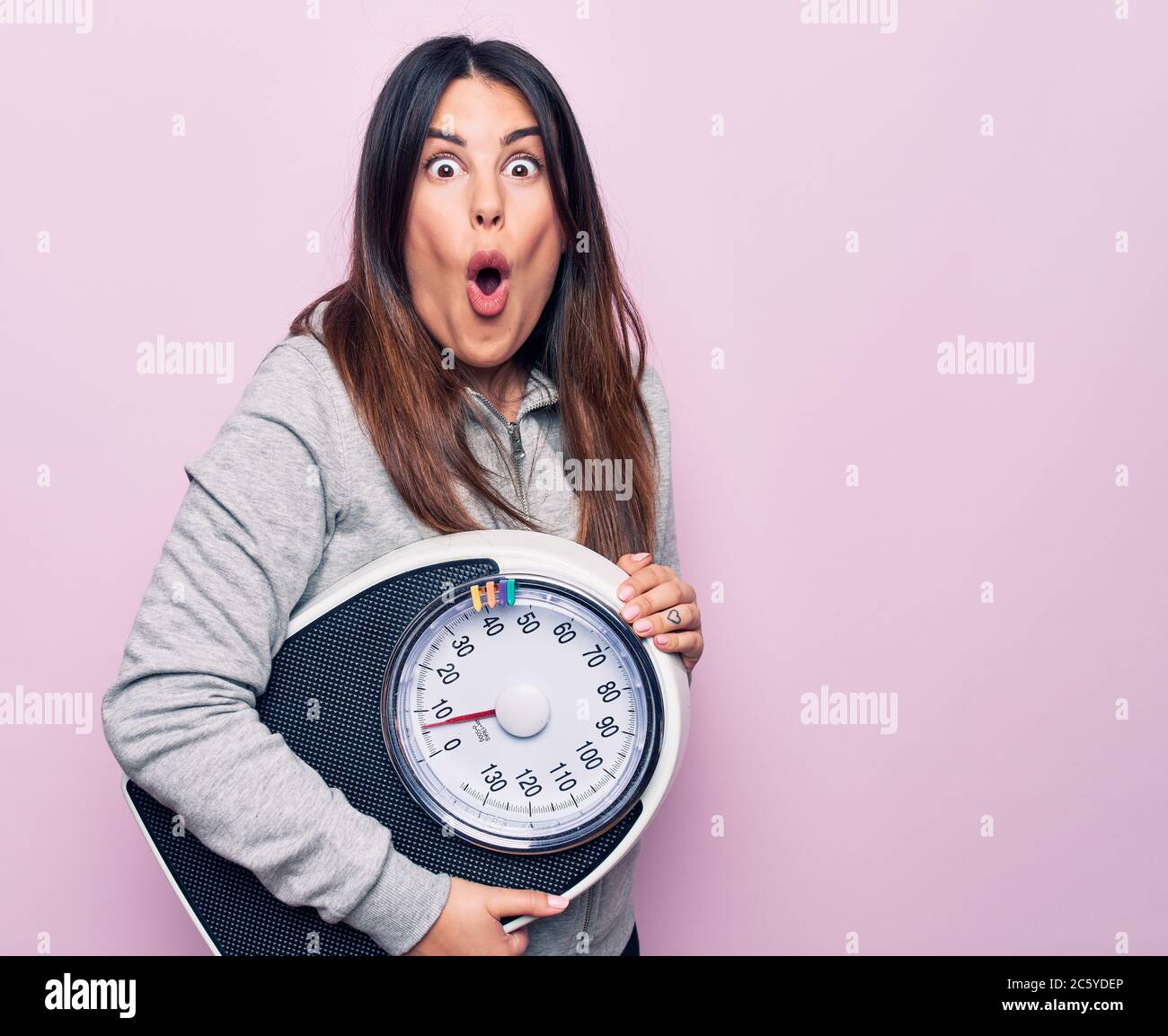 Young beautiful brunette sporty woman controlling weight using ...