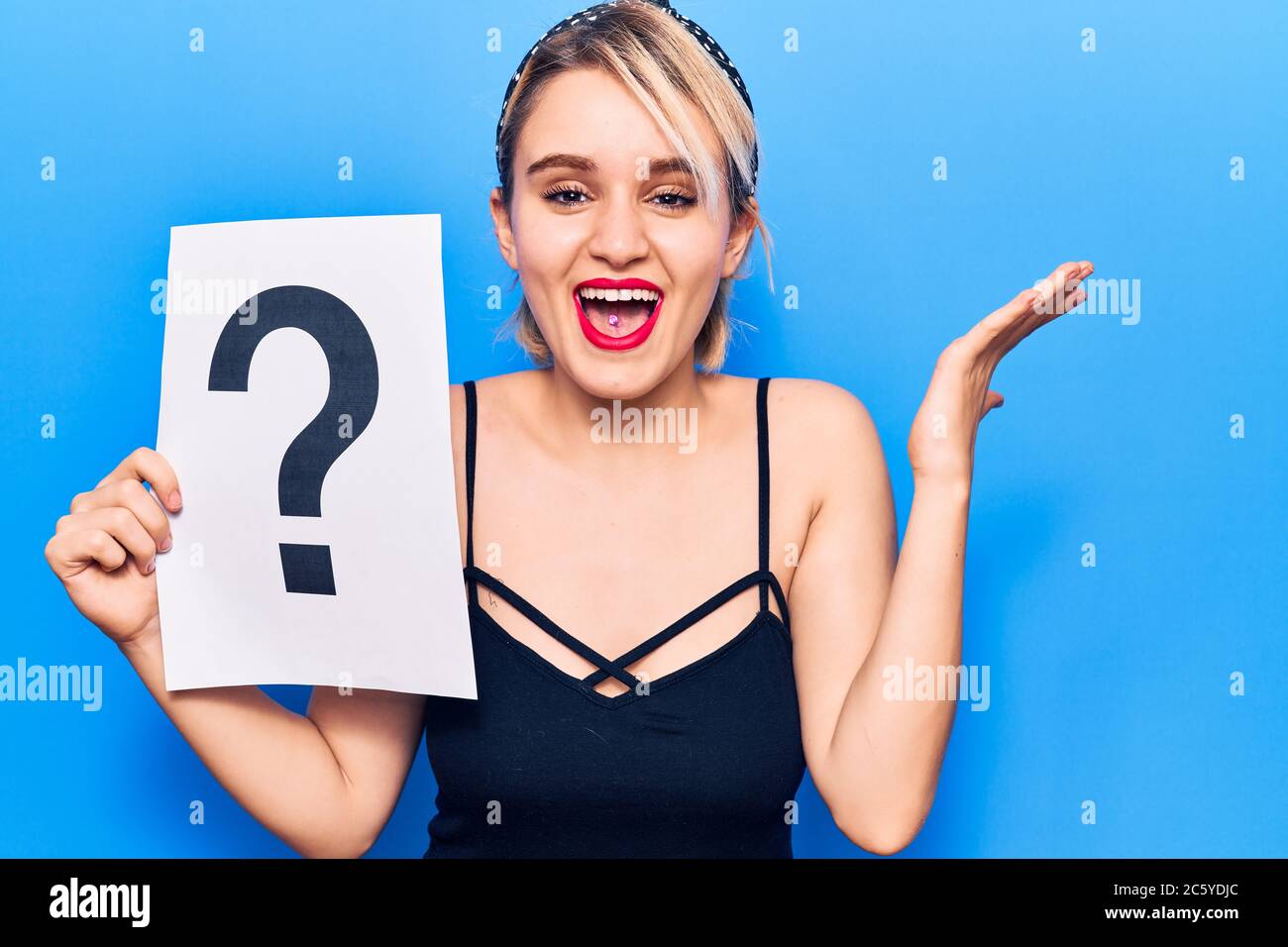 Young beautiful blonde woman holding question mark celebrating victory ...