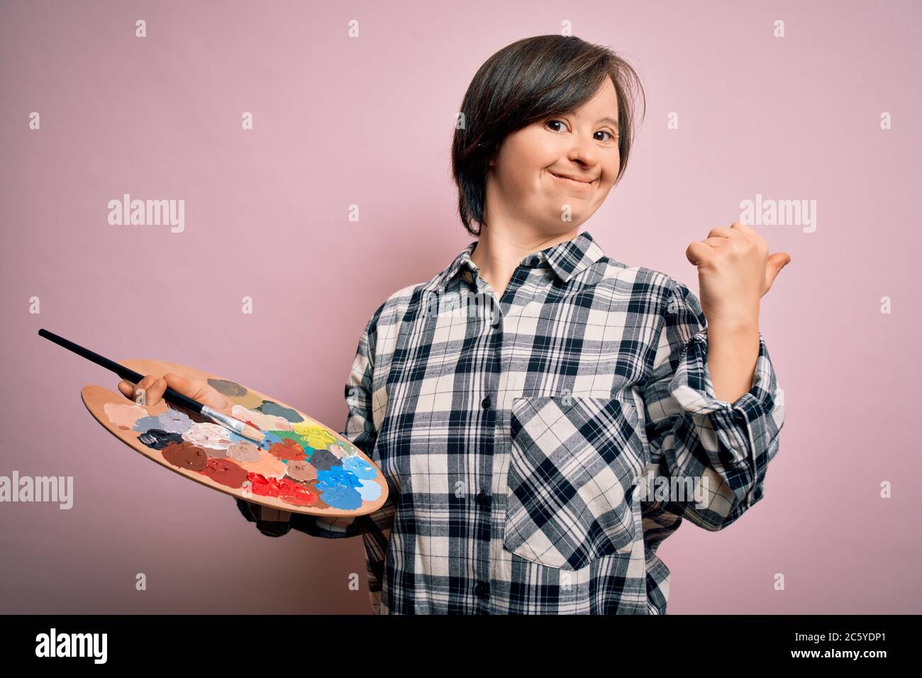 Young down syndrome artist woman holding painter palette and paintbrush ...