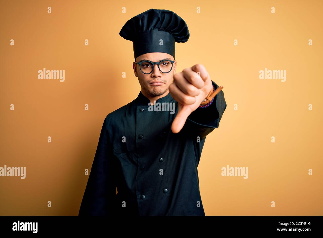Young brazilian chef man wearing cooker uniform and hat over isolated ...
