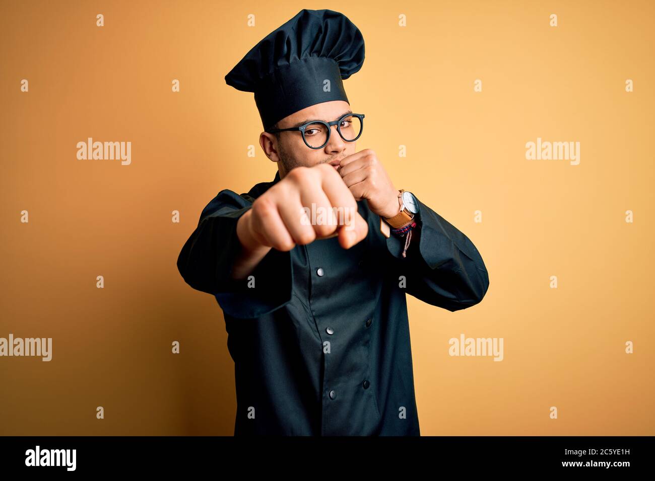 Young brazilian chef man wearing cooker uniform and hat over isolated ...