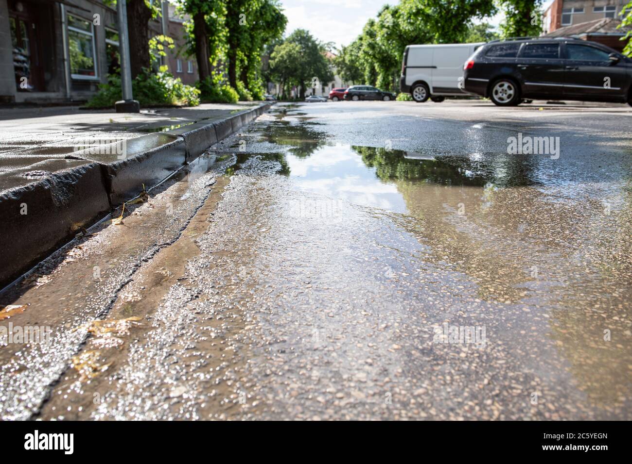 Streets after heavy summer rain with puddles, parked cars on side Stock ...