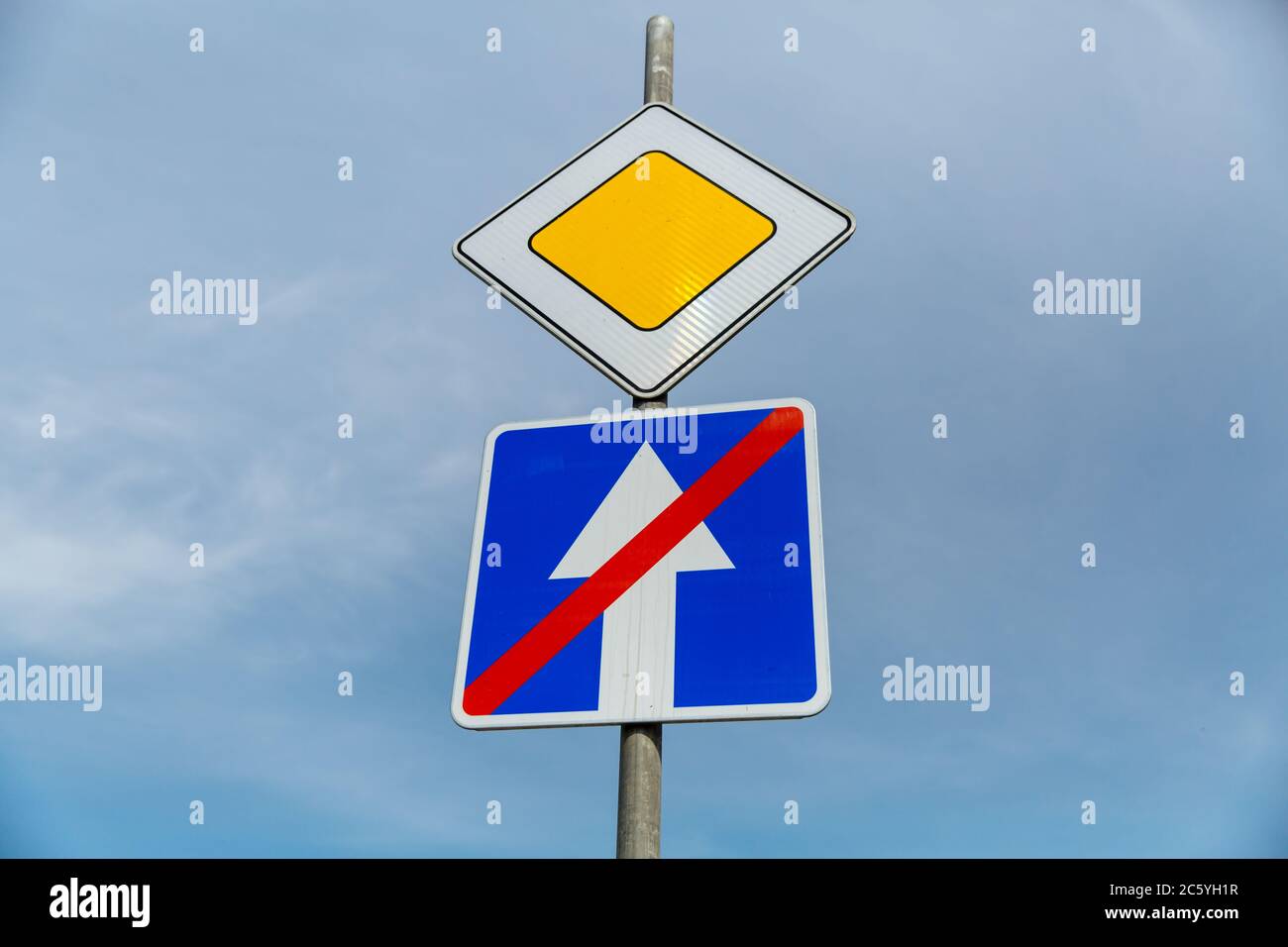 Road sign main road and one-way road end sign on blue sky background ...