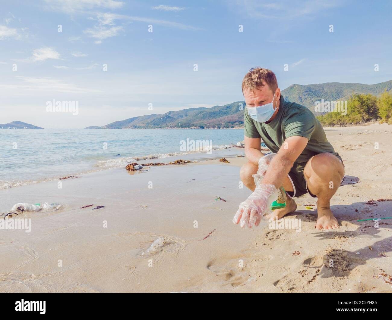 Man in gloves pick up plastic that pollute sea and forest. Problem of ...