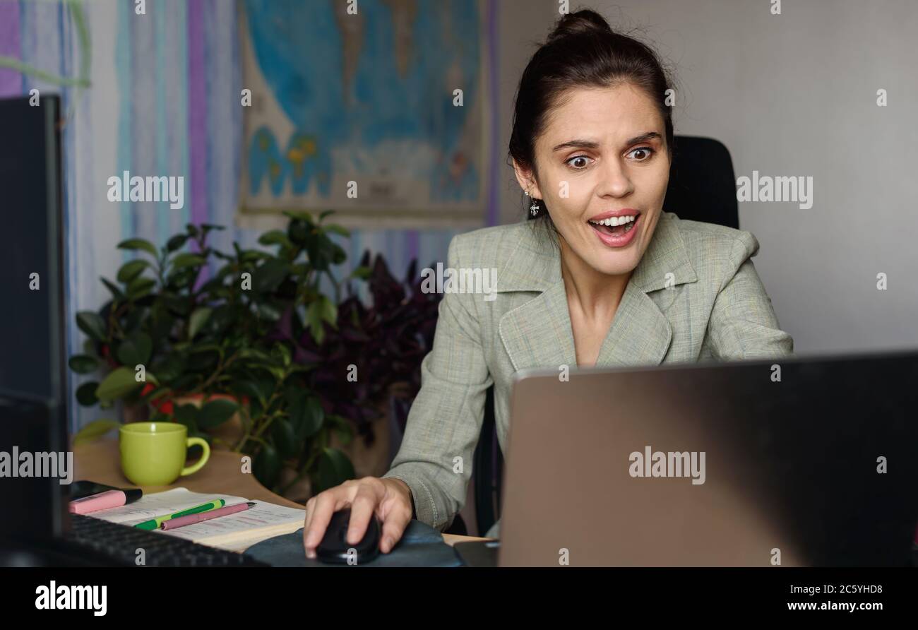 Shocked business woman using laptop looking at computer screen at home ...
