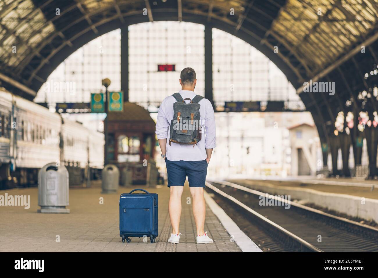 man at railway station waiting for late train with bag Stock Photo - Alamy