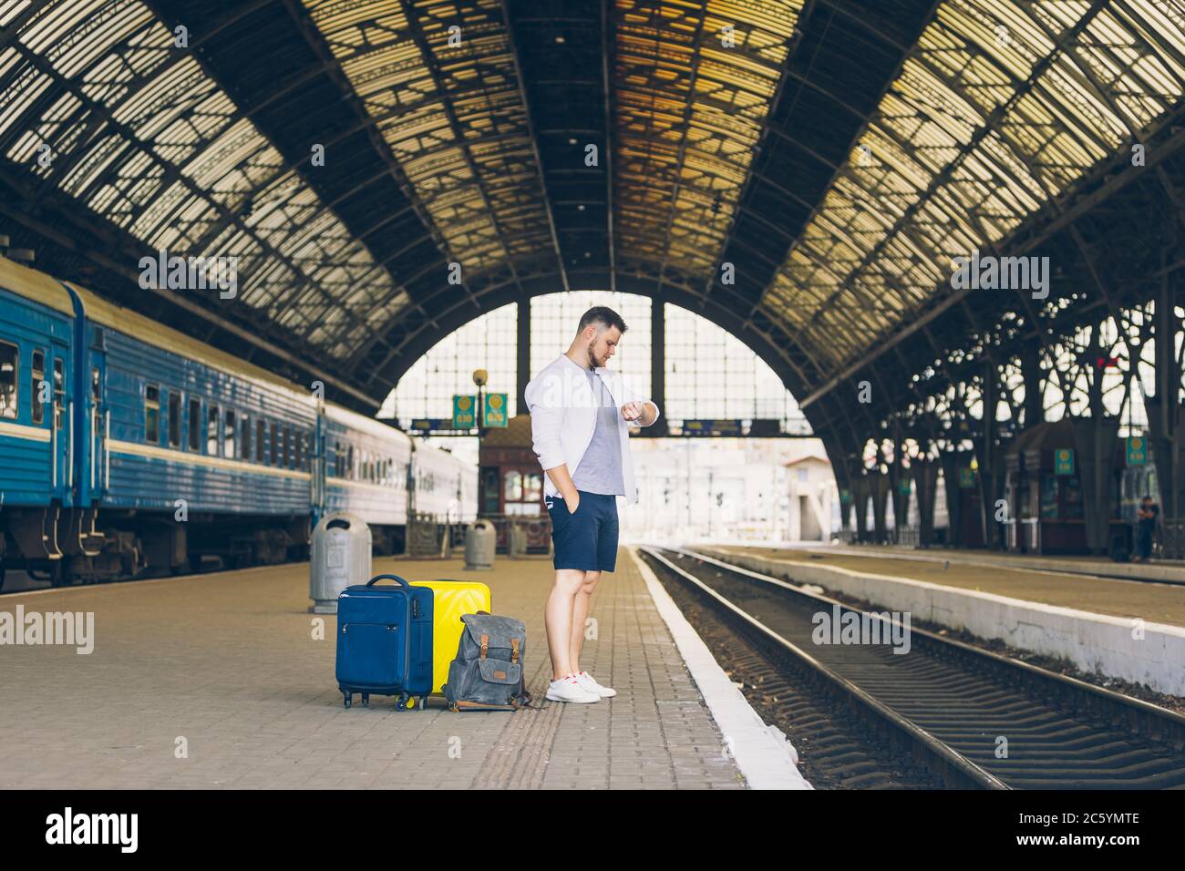 man at railway station waiting for late train with bag looking at watch ...