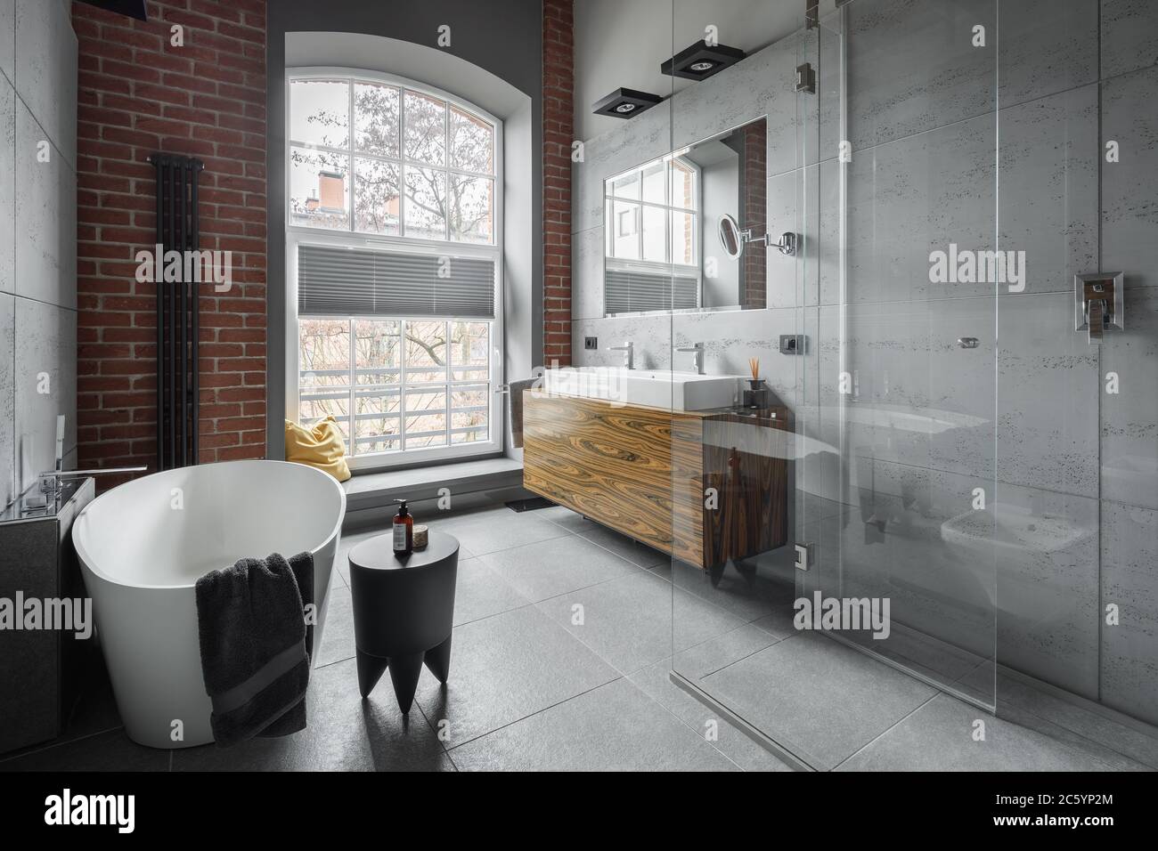 Industrial style bathroom with oval bathtub and walk in shower Stock ...
