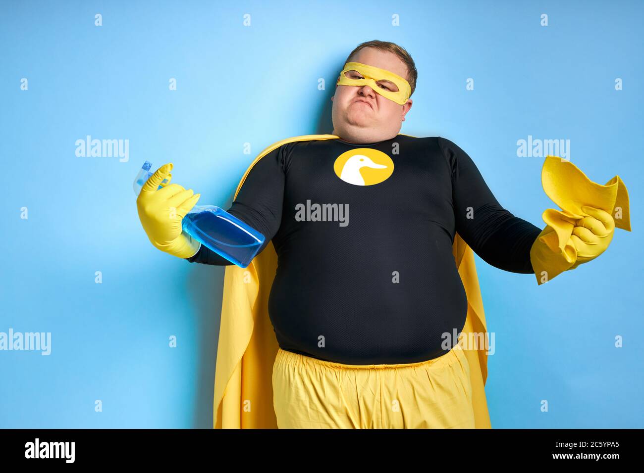 overweight young superhero man uses detergents and rag for cleaning the ...