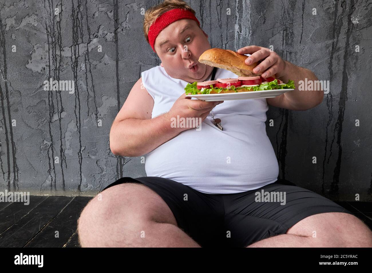 shocked caucasian fat man is opening big sandwich, looks at sausage and ...