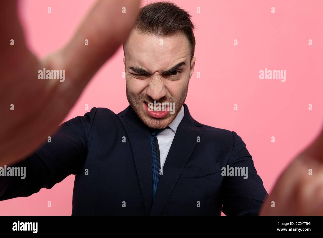 young elegant businessman in suit making silly faces, holding and ...