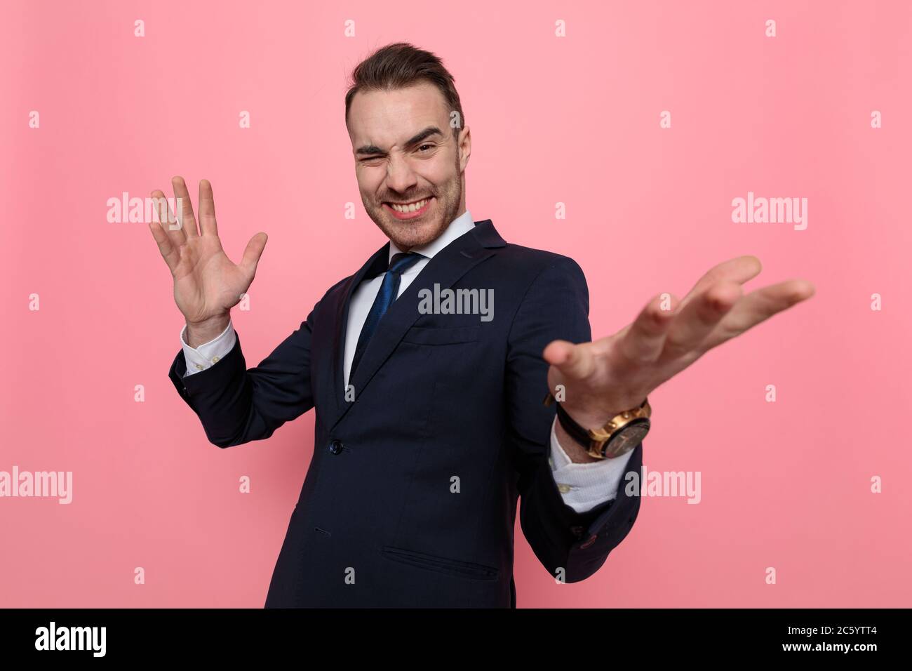 enthusiastic young guy in suit holding hands in the air and presenting ...