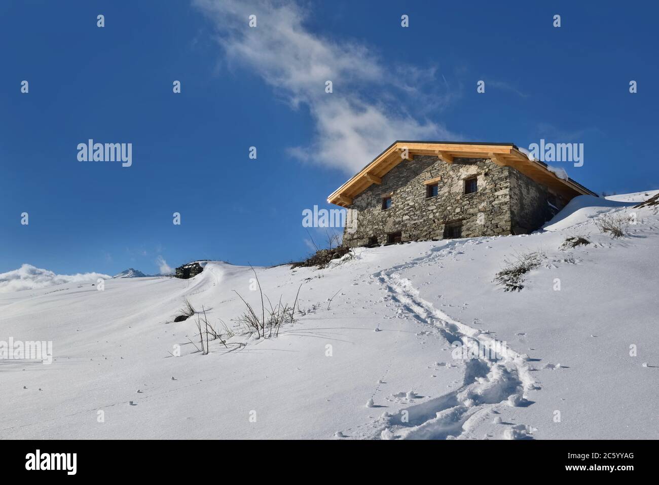 traditional alpine chalet at the top of snowy mountain under blue sky ...