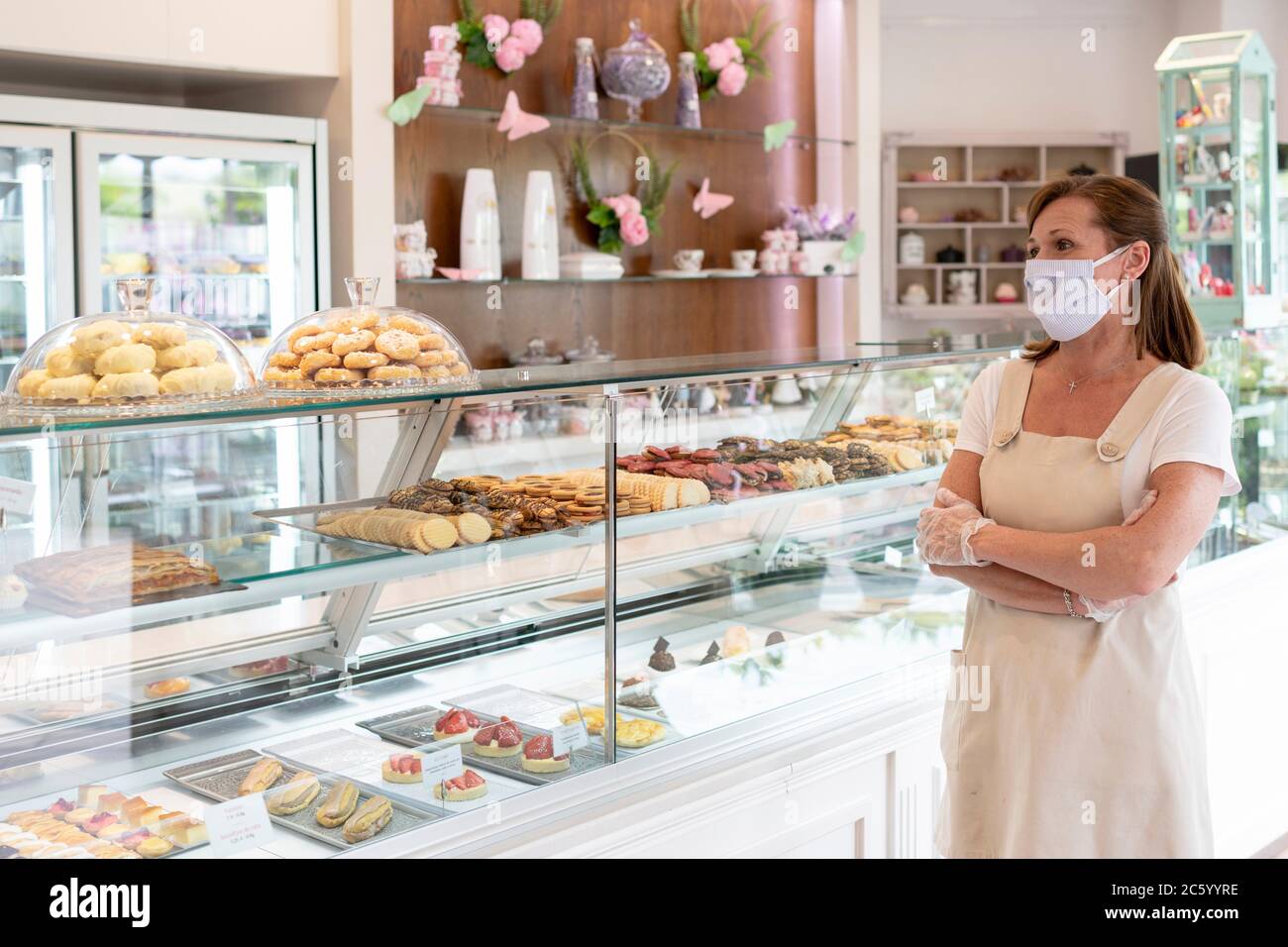 female bakery owner behind counter wearing protection mask due to the ...