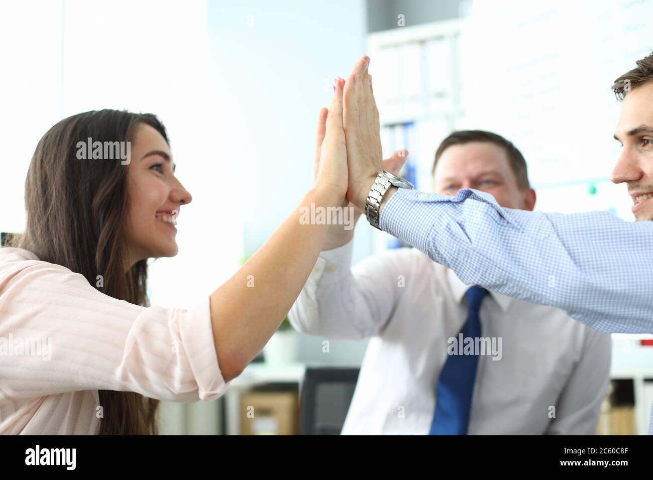 Smiling employees celebrating success at work place Stock Photo - Alamy