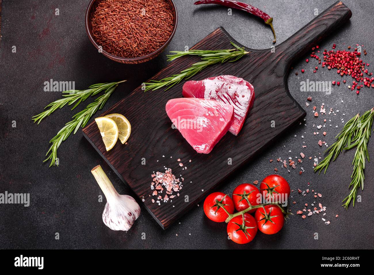 Fresh tuna fillet steaks with spices and herbs on a black background ...