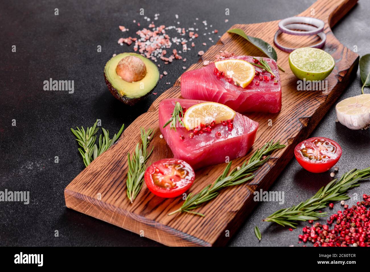 Fresh tuna fillet steaks with spices and herbs on a black background ...