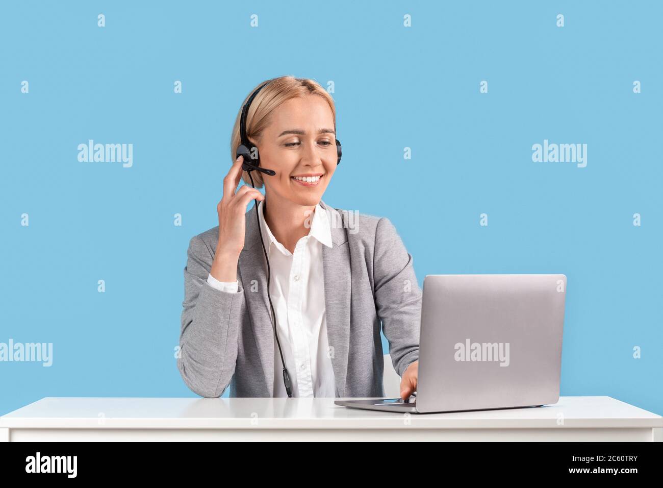 Beautiful mature helpline operator with headset and laptop answering ...